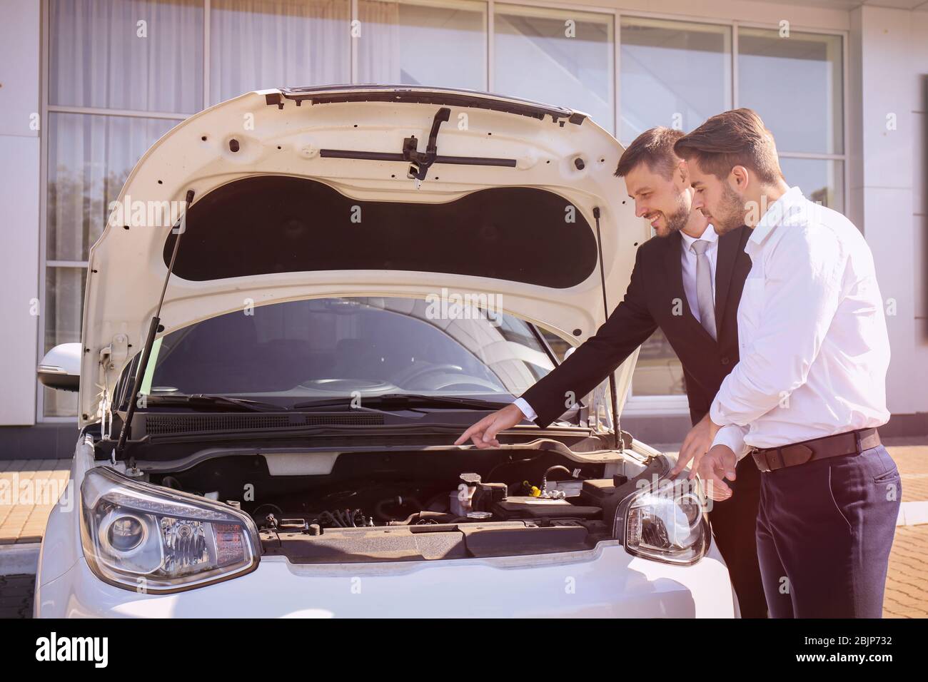 Salesman showing new car to customer outdoors Stock Photo - Alamy