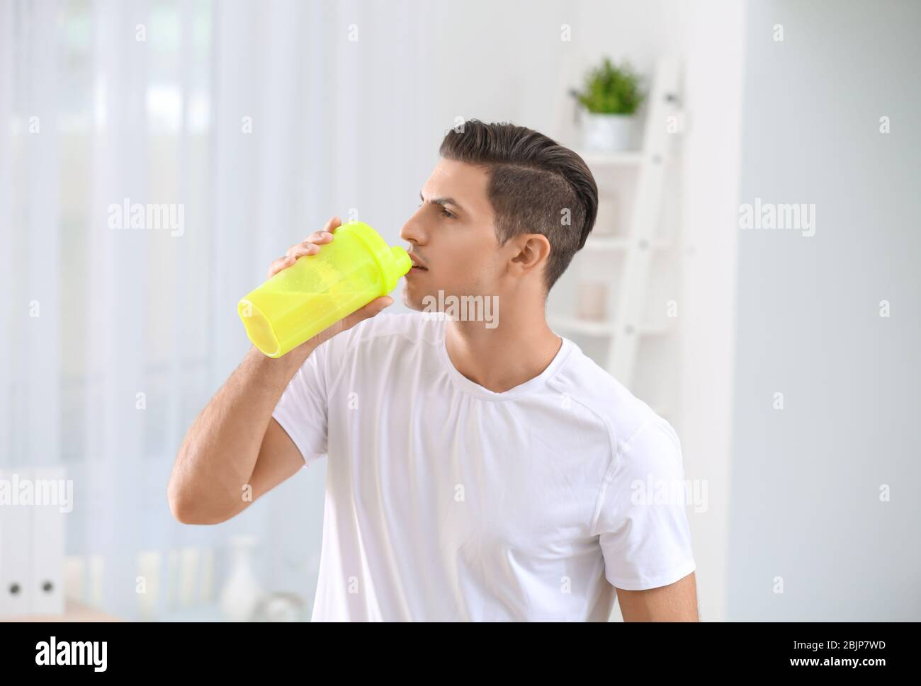 Young man drinking protein shake indoors Stock Photo - Alamy