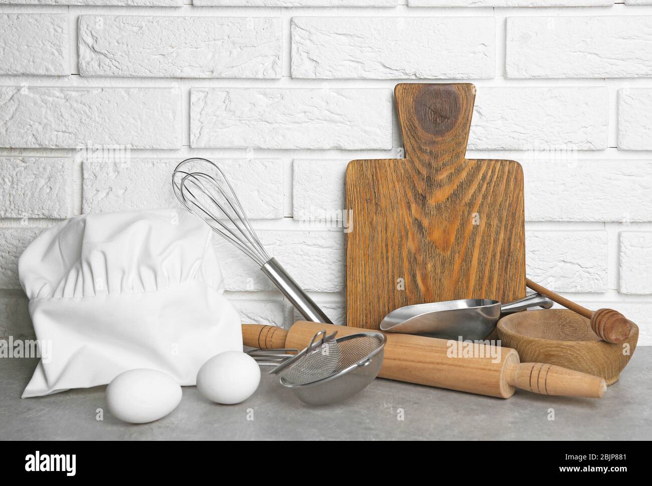 Set of kitchen utensils on table against white wall Stock Photo - Alamy