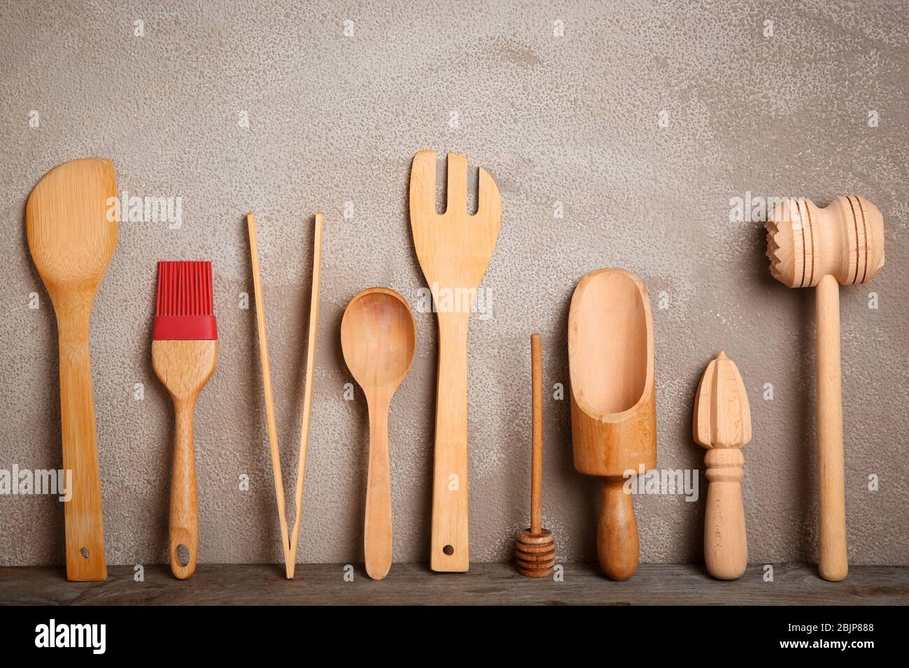 Wooden kitchen utensils on table against wall Stock Photo - Alamy