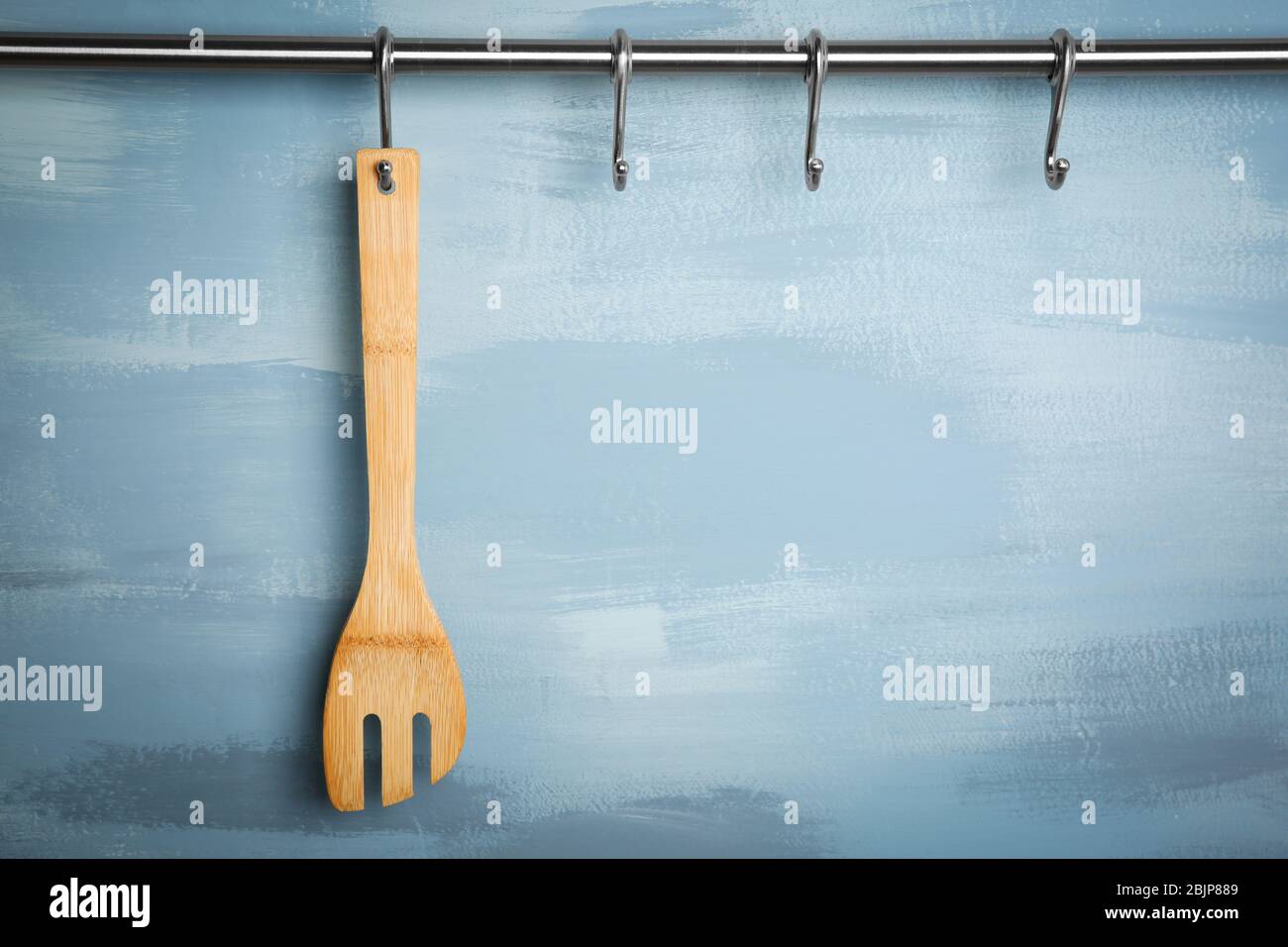 Wooden fork hanging on rack against color wall Stock Photo - Alamy