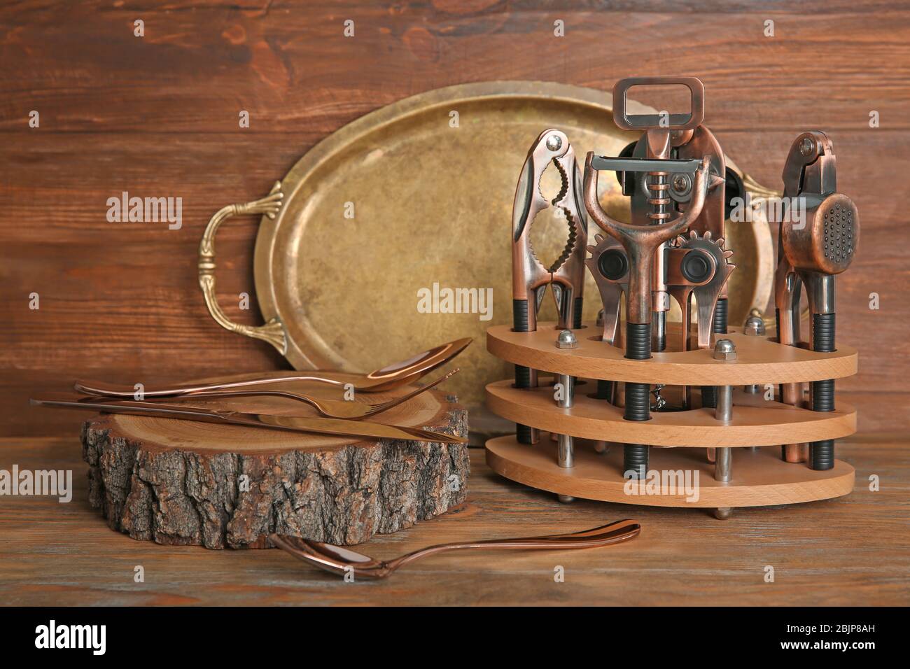 Stand with kitchen utensils and cutlery on table against wooden wall ...
