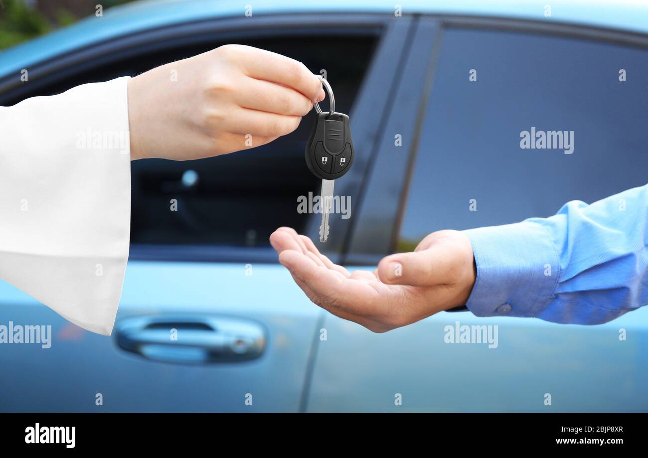 Saleswoman giving car key to customer outdoors Stock Photo - Alamy