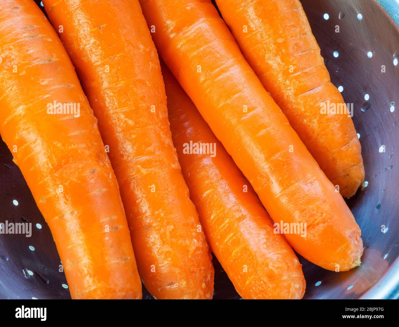 Five washed orange carrots in a stainless steel colander Stock Photo ...