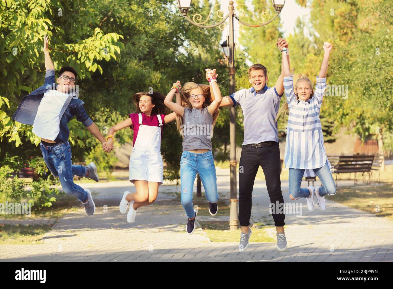 Happy teenagers jumping on city street Stock Photo - Alamy