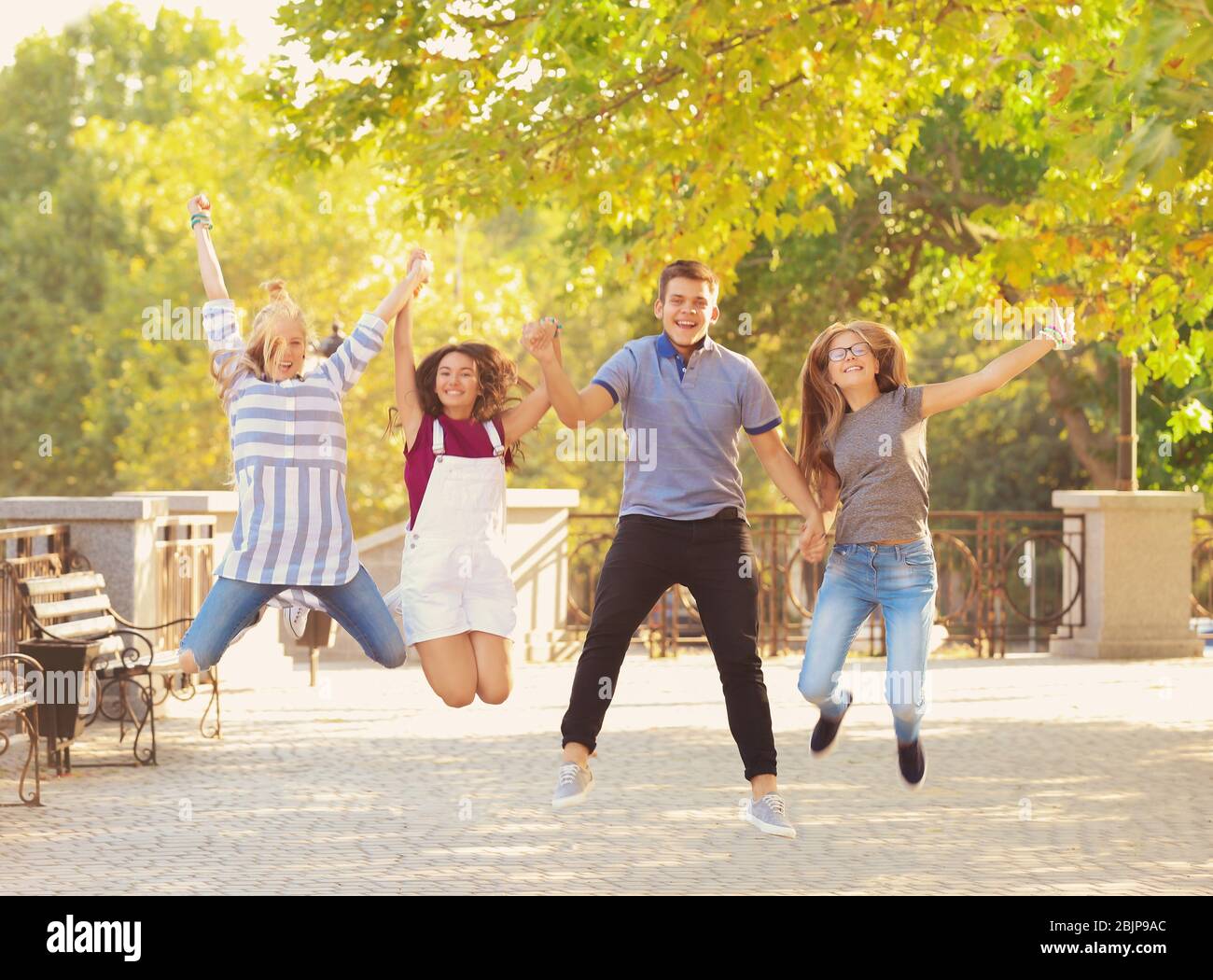 Happy teenagers jumping on city street Stock Photo - Alamy