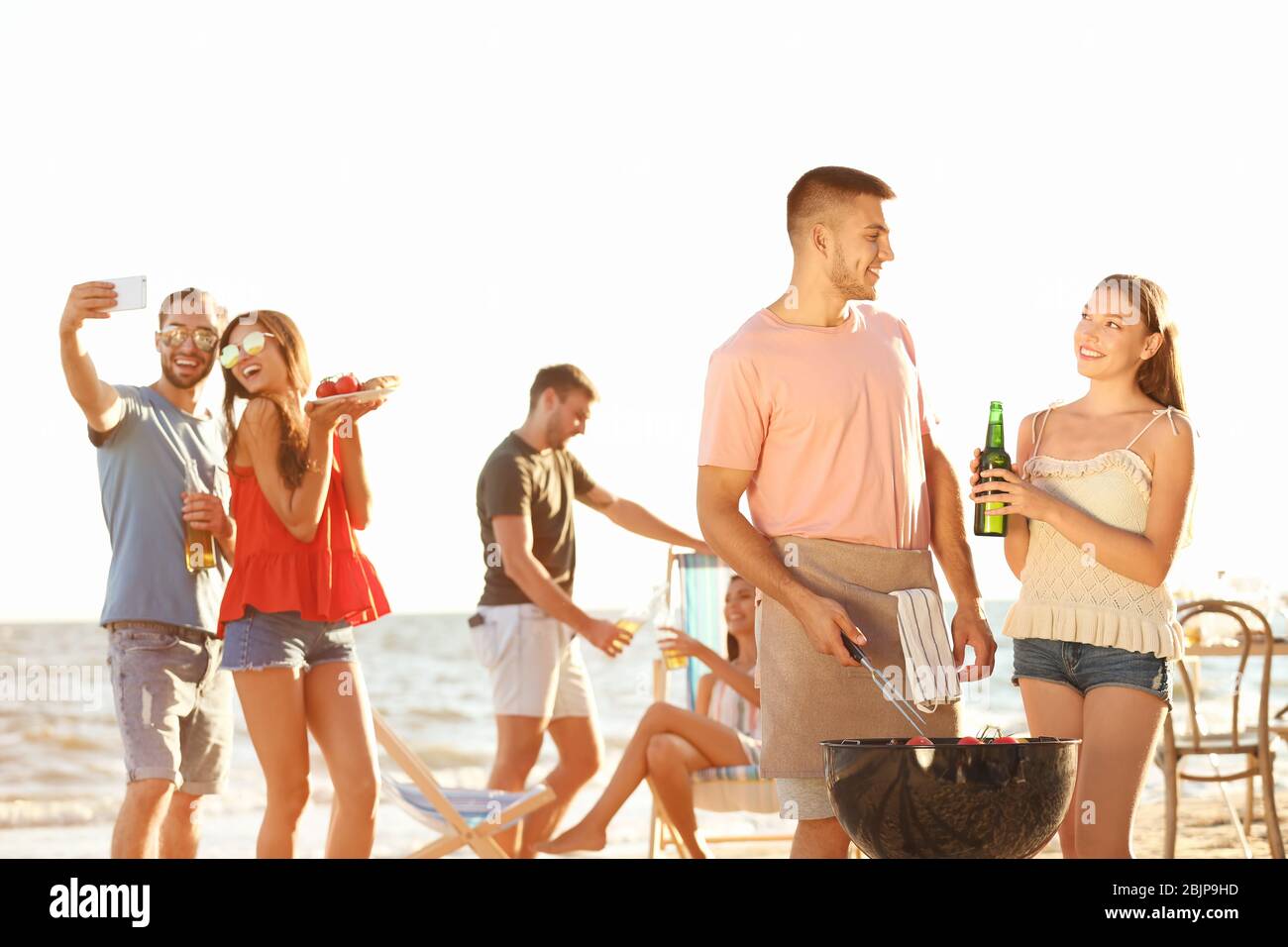 Young people having barbecue party on beach Stock Photo - Alamy