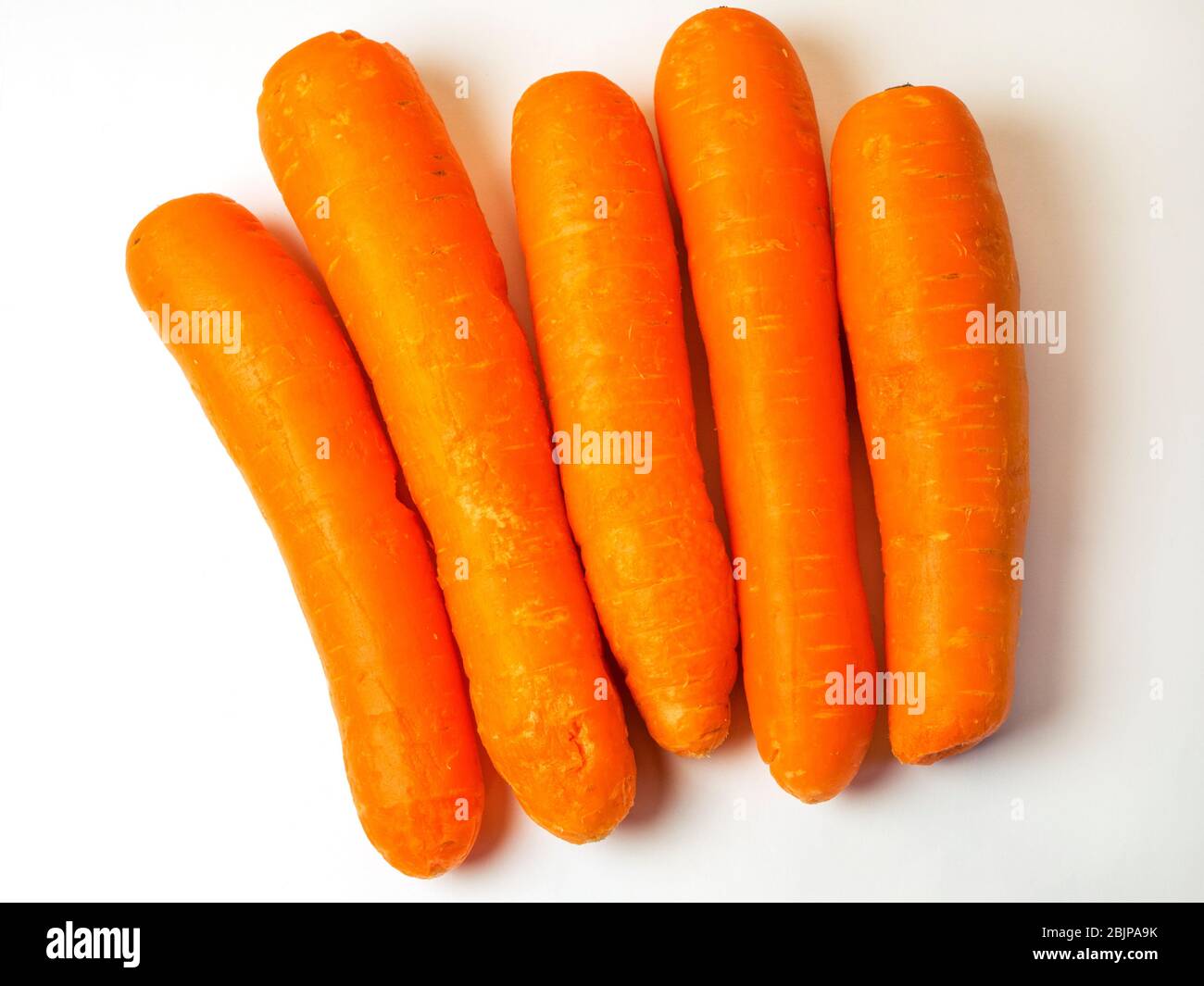 Five fresh orange carrots on a white background Stock Photo - Alamy