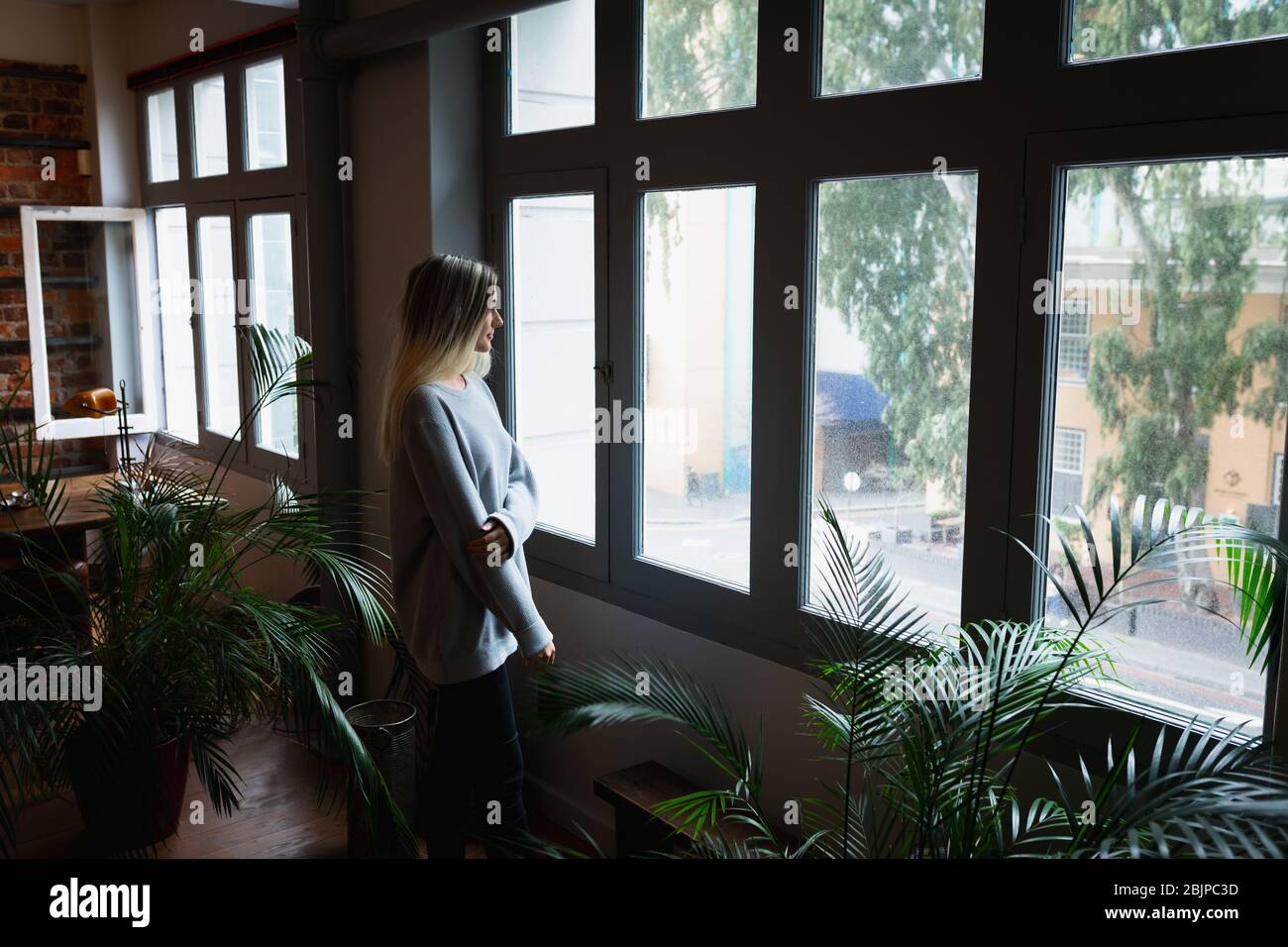 Young woman looking through the window Stock Photo - Alamy