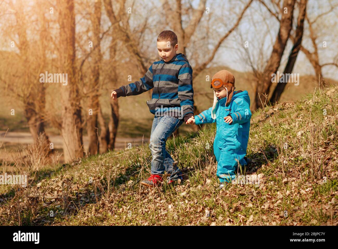Happy children on the walk in sunny forest or park. Outdoor activities ...