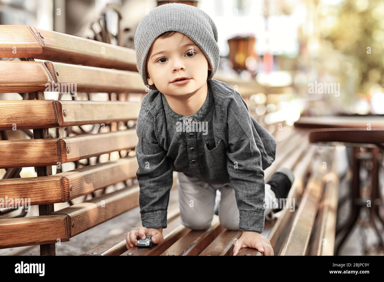 Adorable little boy on bench in outdoor cafe Stock Photo - Alamy