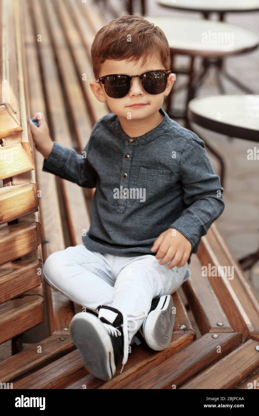 Adorable little boy sitting on bench in outdoor cafe Stock Photo - Alamy