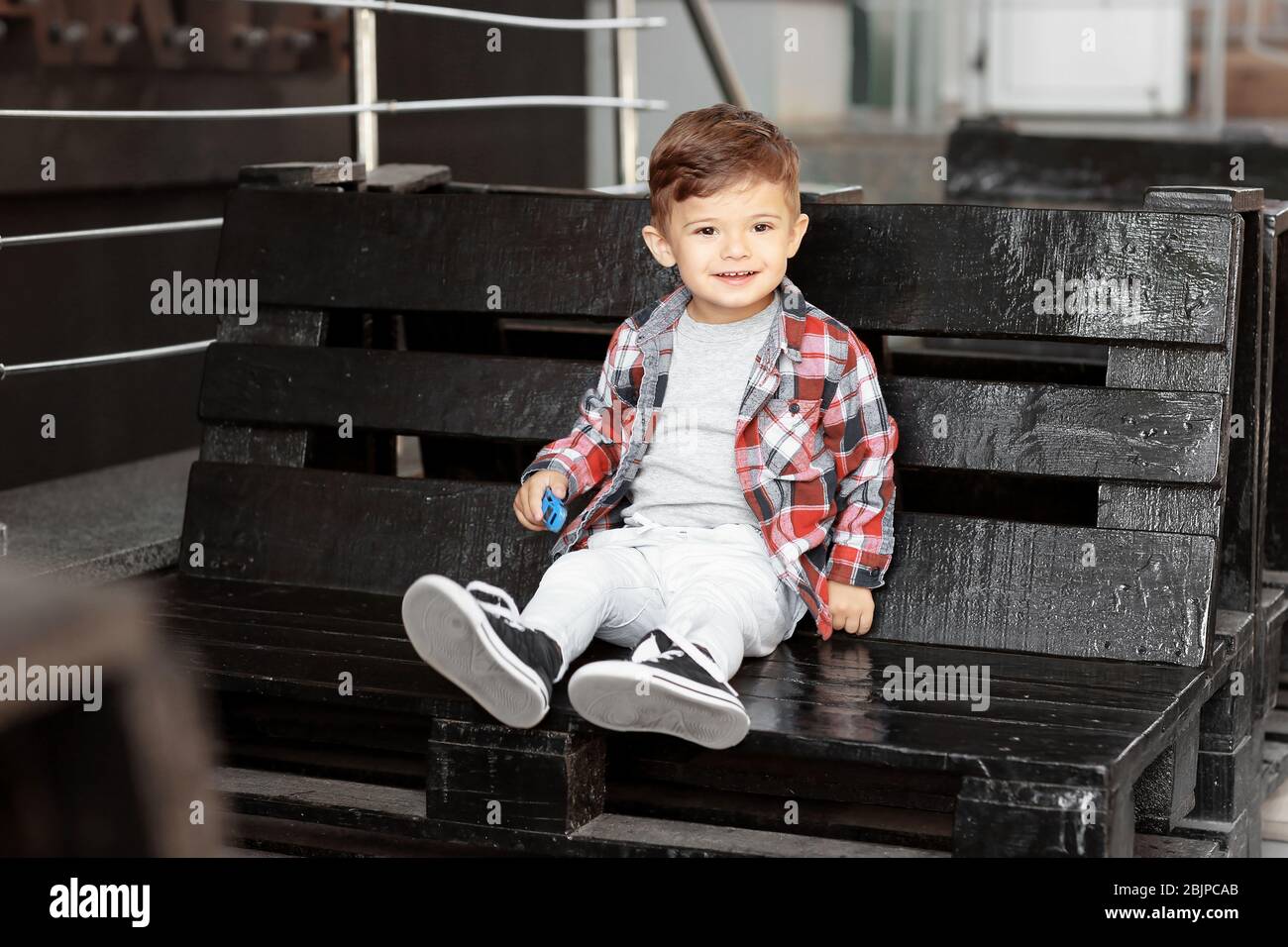 Adorable little boy sitting on bench in outdoor cafe Stock Photo - Alamy