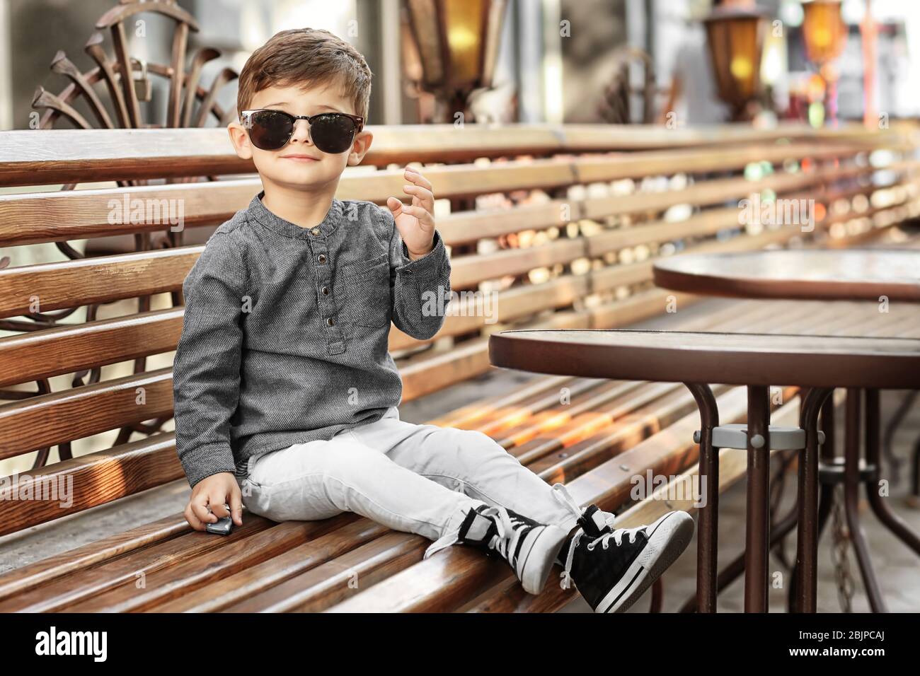 Adorable little boy sitting on bench in outdoor cafe Stock Photo - Alamy