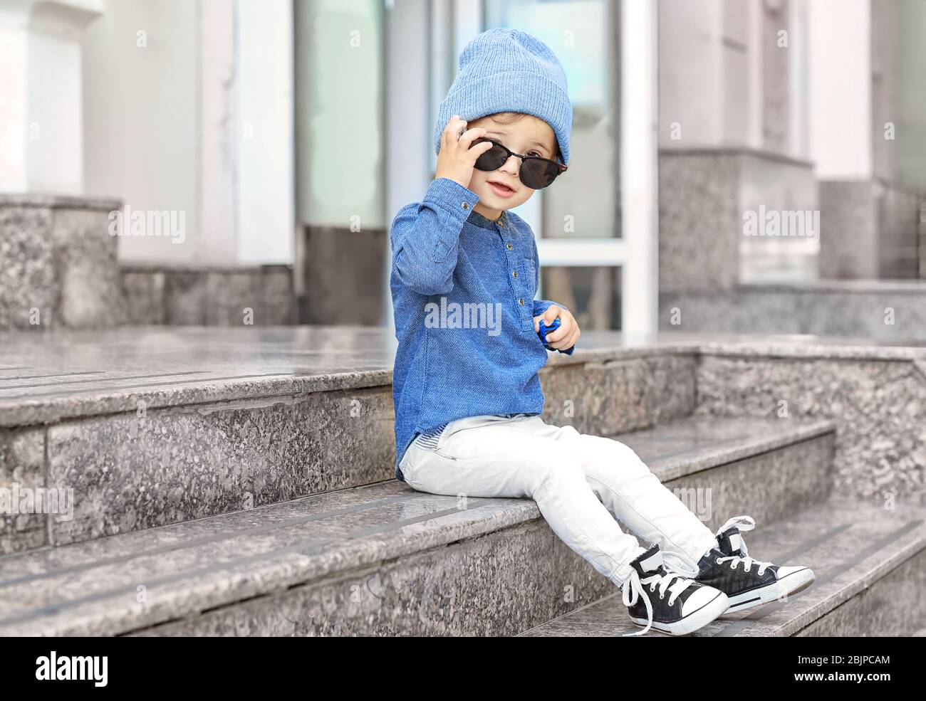 Adorable little boy sitting on stairs outdoors Stock Photo - Alamy