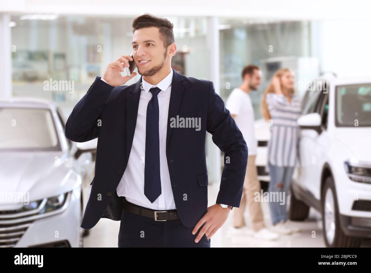 Car salesman talking on phone in dealership Stock Photo - Alamy