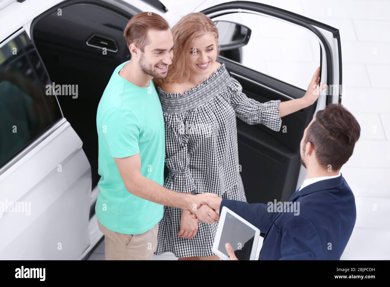 Car salesman and young couple in dealership Stock Photo - Alamy