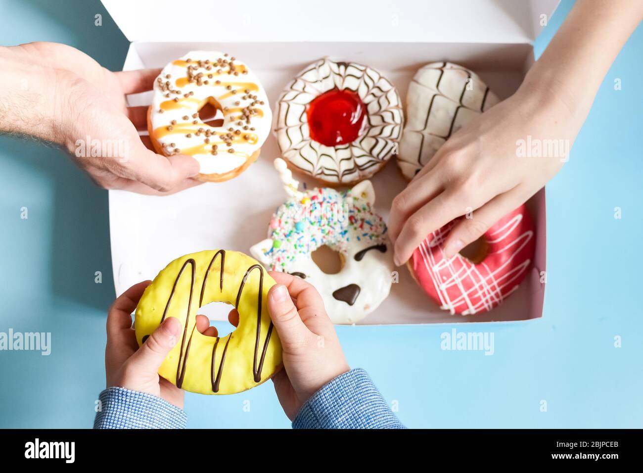 People hands takes donuts from donuts box over blue background. Family ...