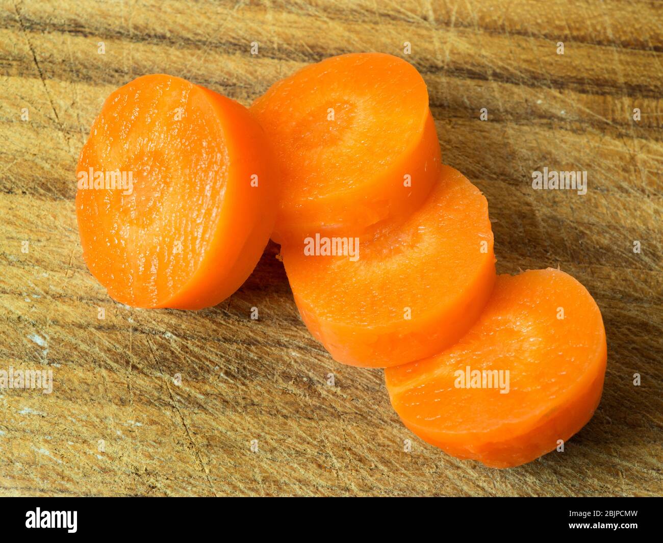 Four carrot slices on a wooden chopping board Stock Photo - Alamy