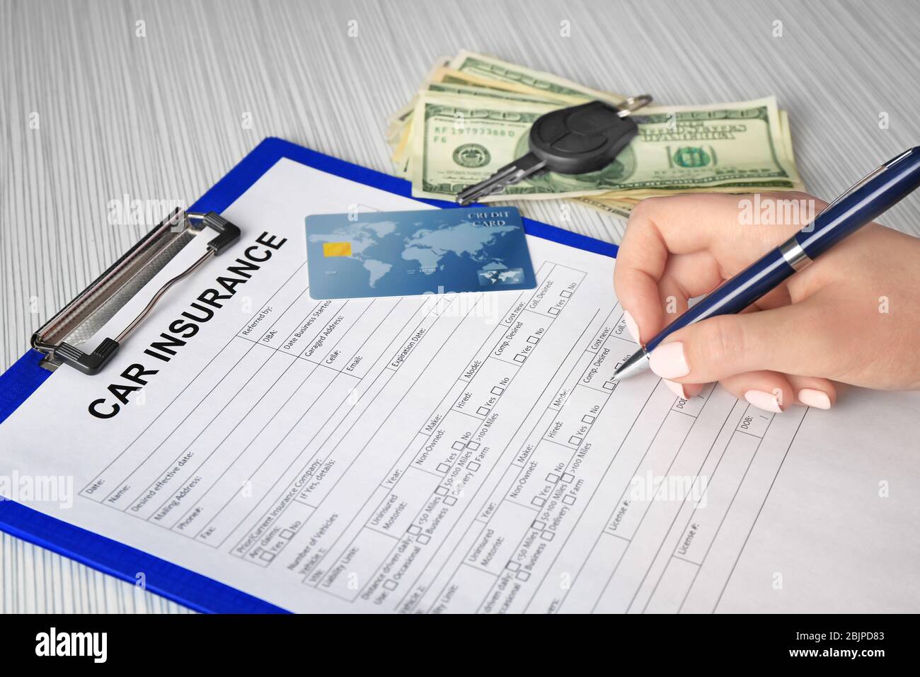 Woman filling in car insurance form at table Stock Photo - Alamy