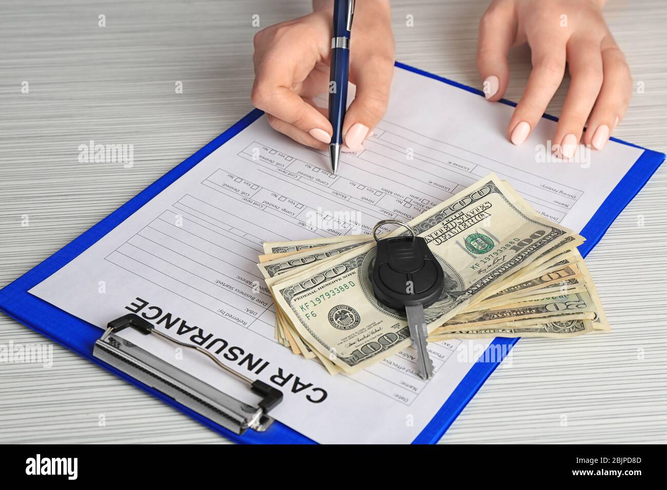 Woman filling in car insurance form at table Stock Photo - Alamy