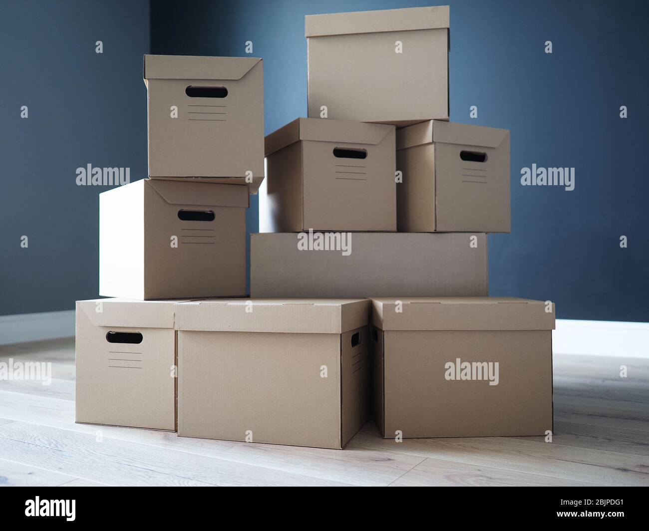 Pile of carton boxes standing in the middle of empty room in new house ...