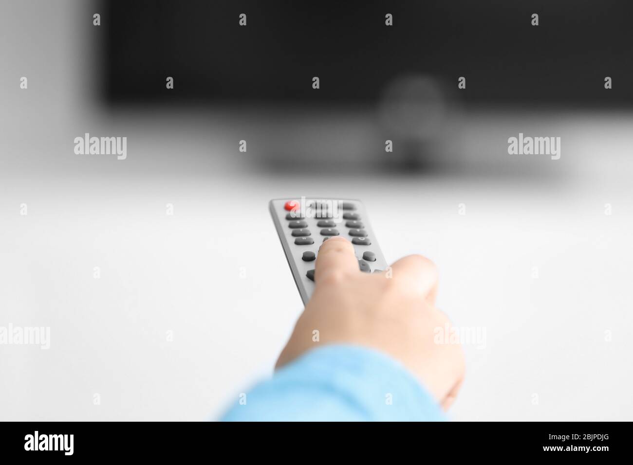 Woman with TV remote control switching channels, closeup Stock Photo ...