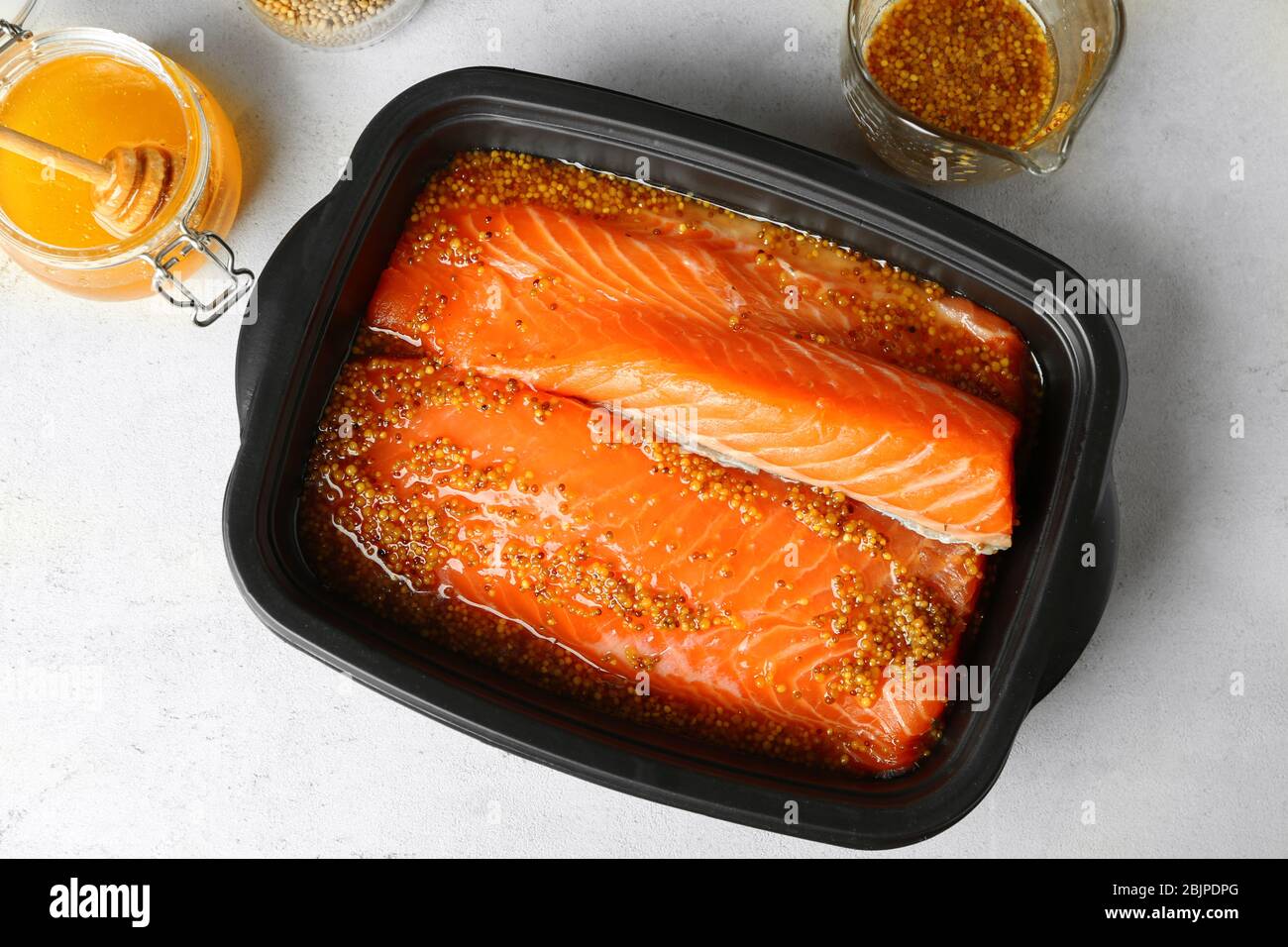 Dish with salmon fillet in honey mustard marinade on table Stock Photo ...