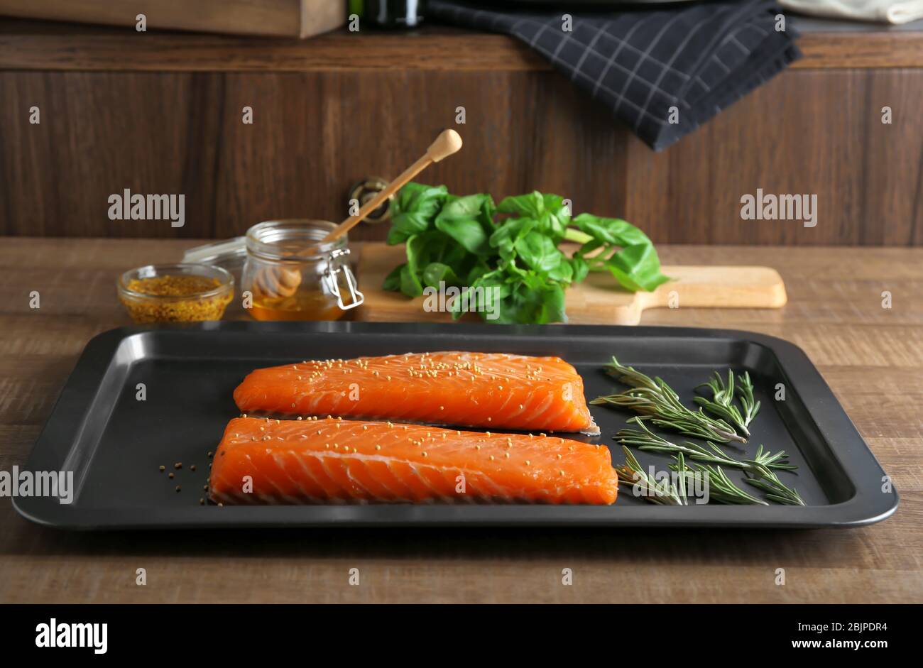 Baking sheet with salmon fillet in honey mustard marinade on table ...