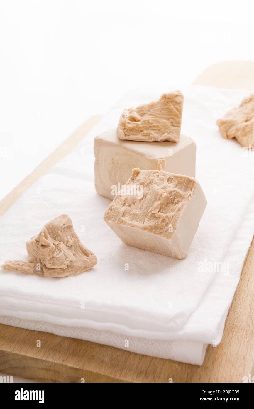 Fresh yeast blocks on wooden board isolated on white background ...
