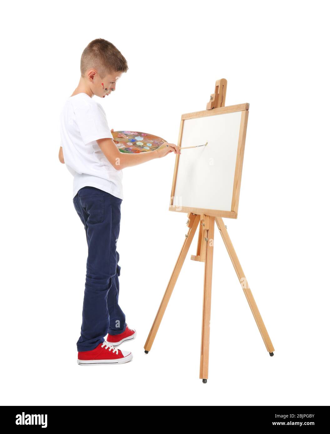 Cute little boy painting picture on canvas against white background ...