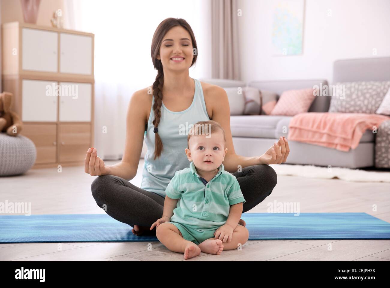 Young mother doing yoga with baby at home Stock Photo - Alamy
