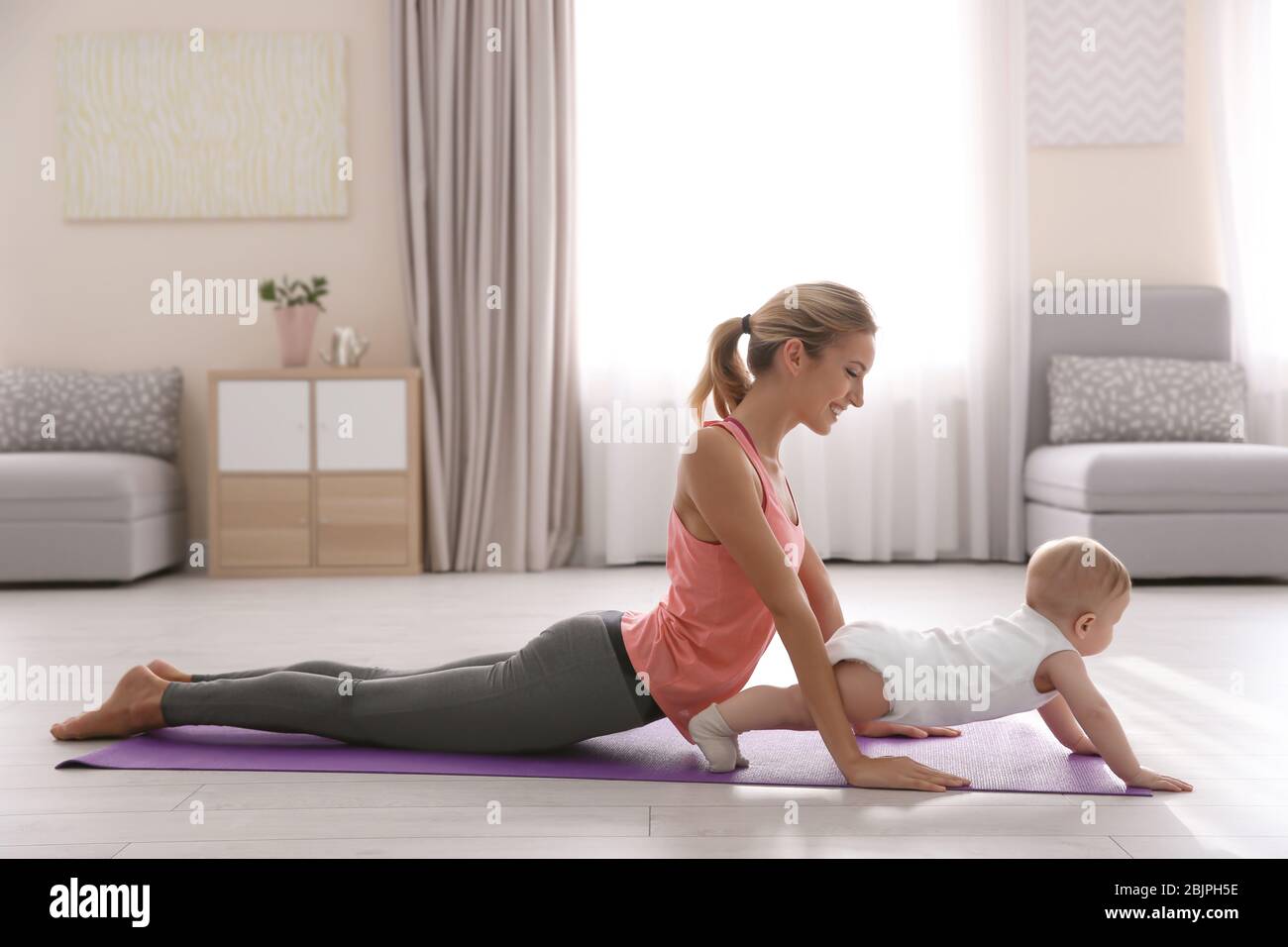 Young mother doing yoga with baby at home Stock Photo - Alamy