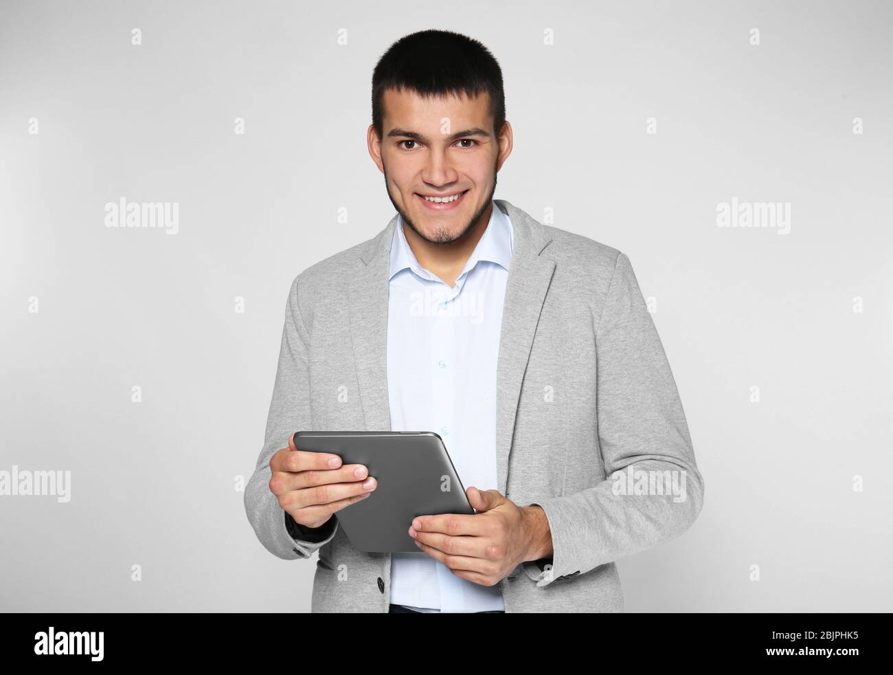 Male manager with tablet computer on grey background Stock Photo - Alamy
