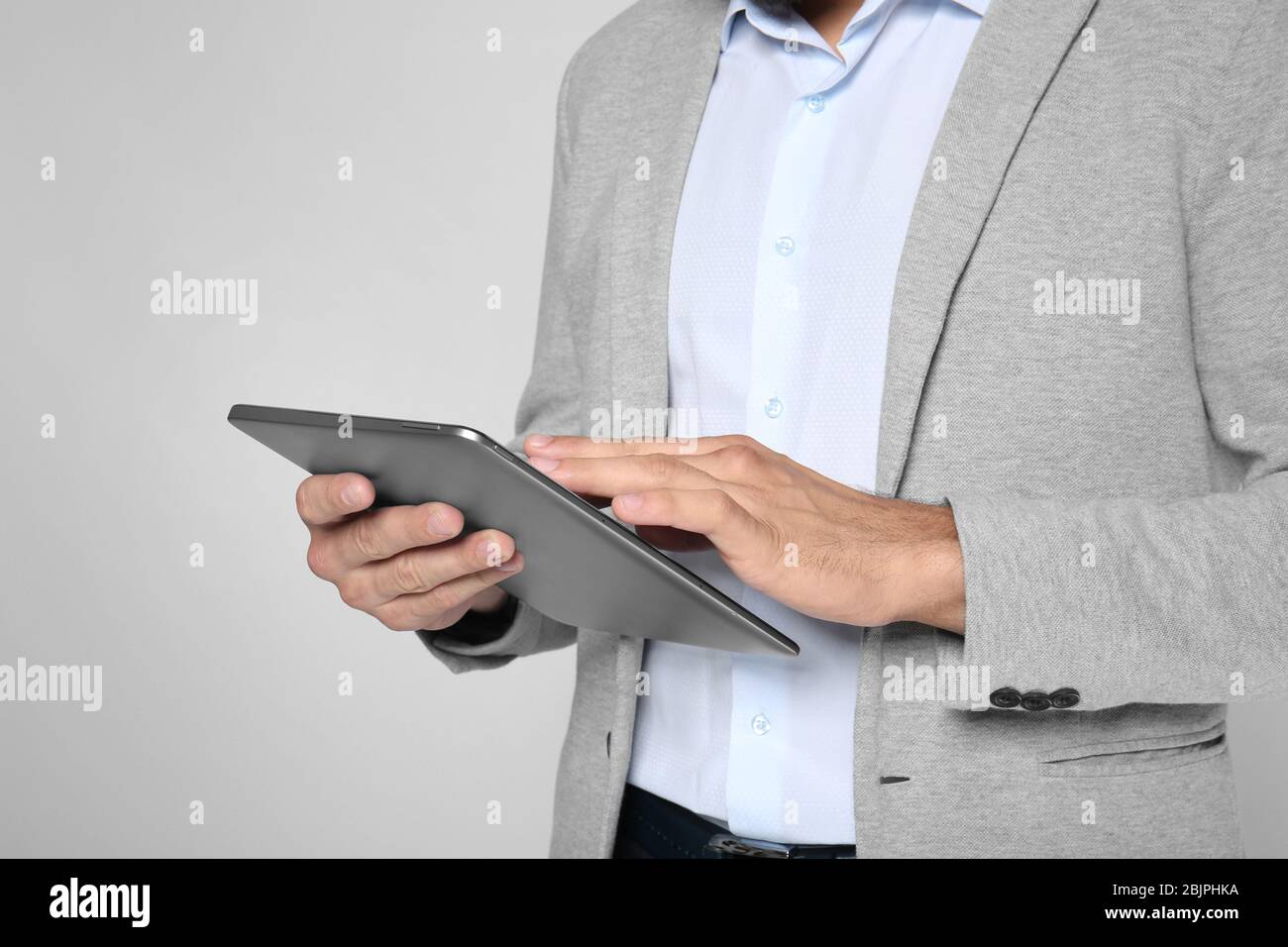 Male manager with tablet computer on grey background Stock Photo - Alamy