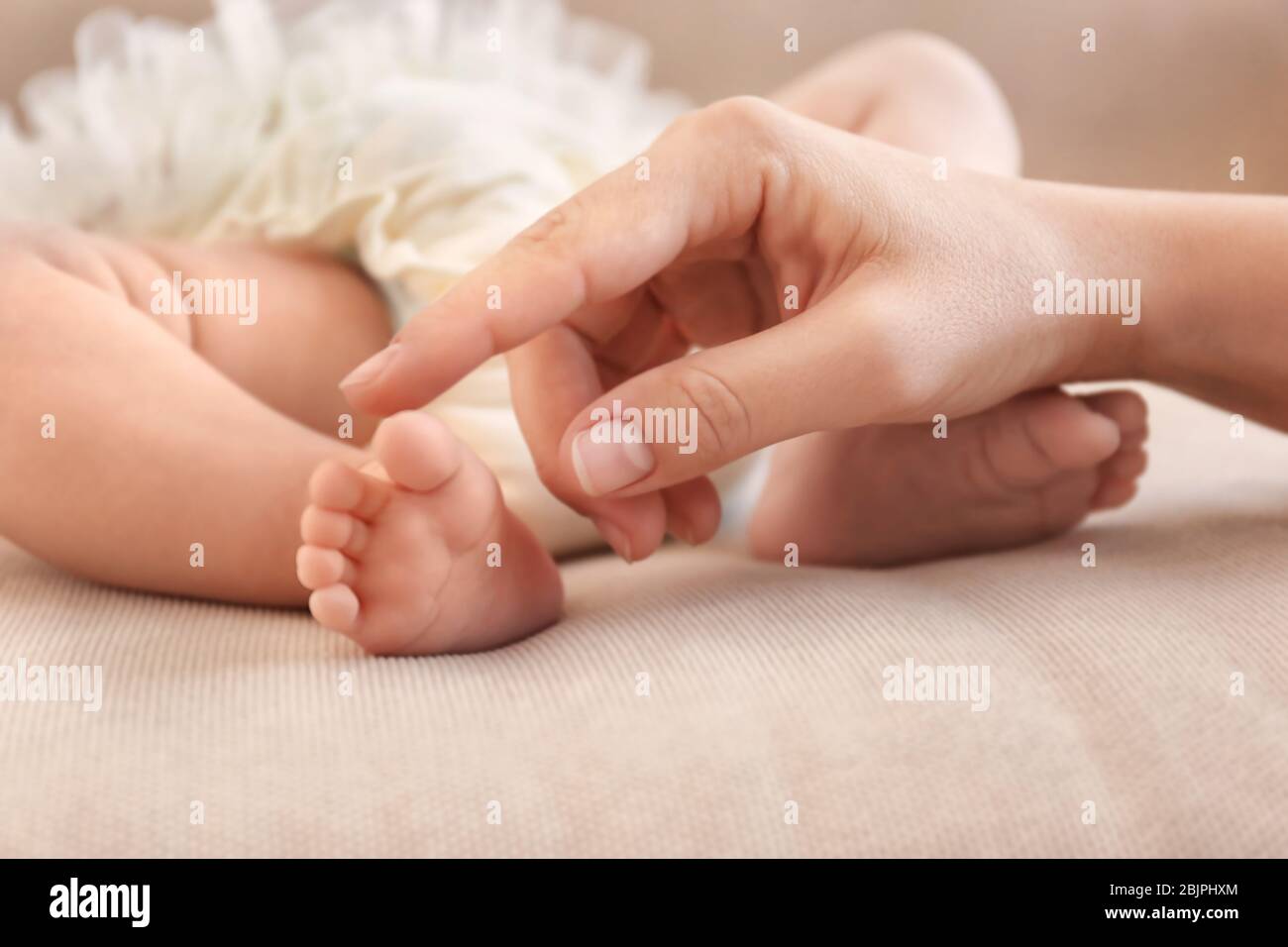 Mother touching baby feet on sofa Stock Photo - Alamy