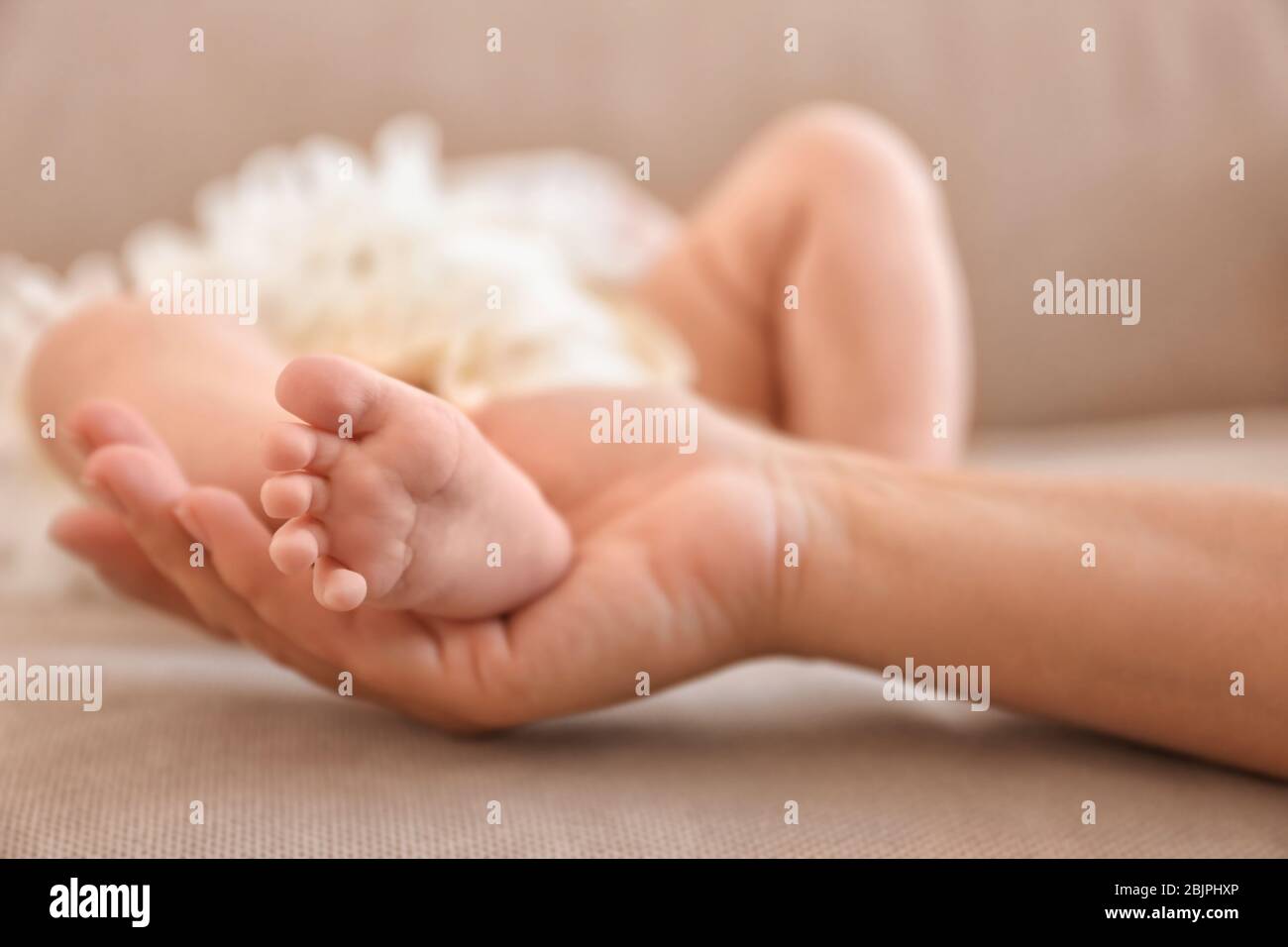 Mother holding leg of baby at home Stock Photo - Alamy