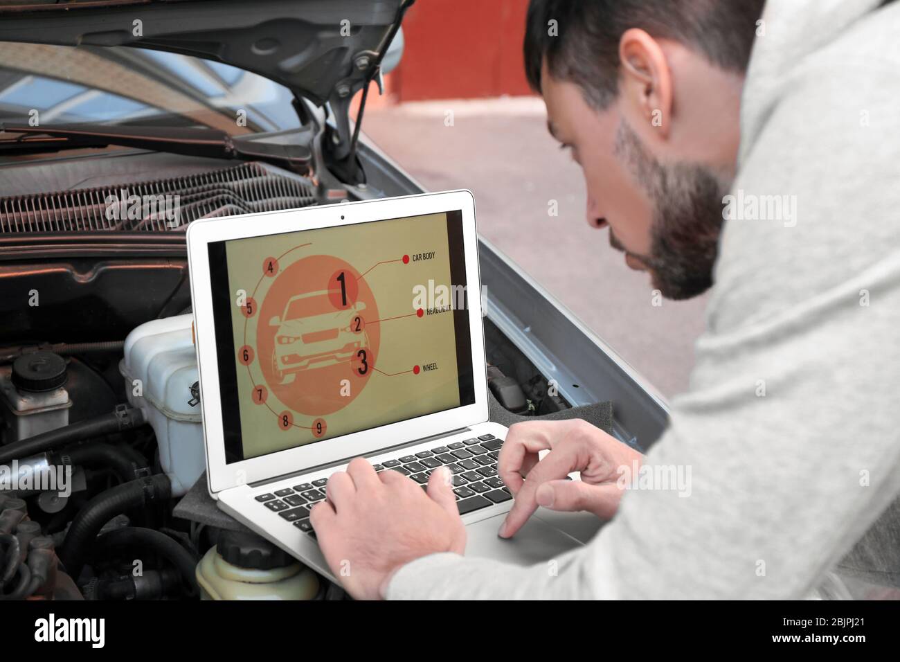 Young male mechanic using computer diagnostic while repairing car Stock ...
