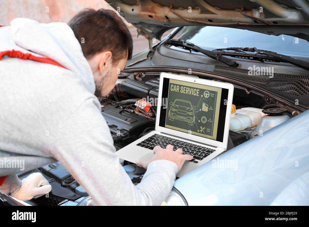 Young male mechanic using computer diagnostic while repairing car Stock ...