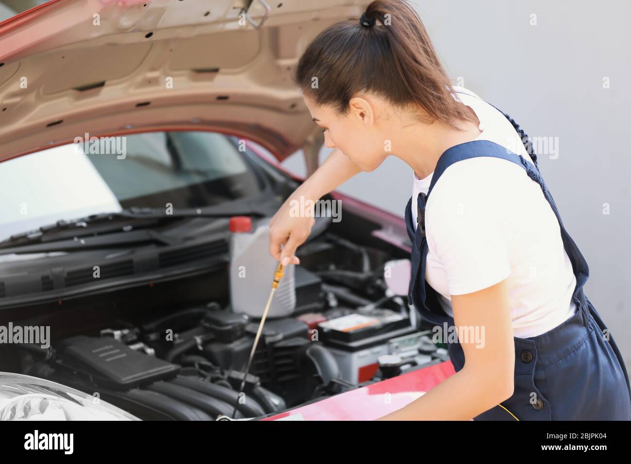 Young mechanic checking car engine oil level outdoors Stock Photo - Alamy