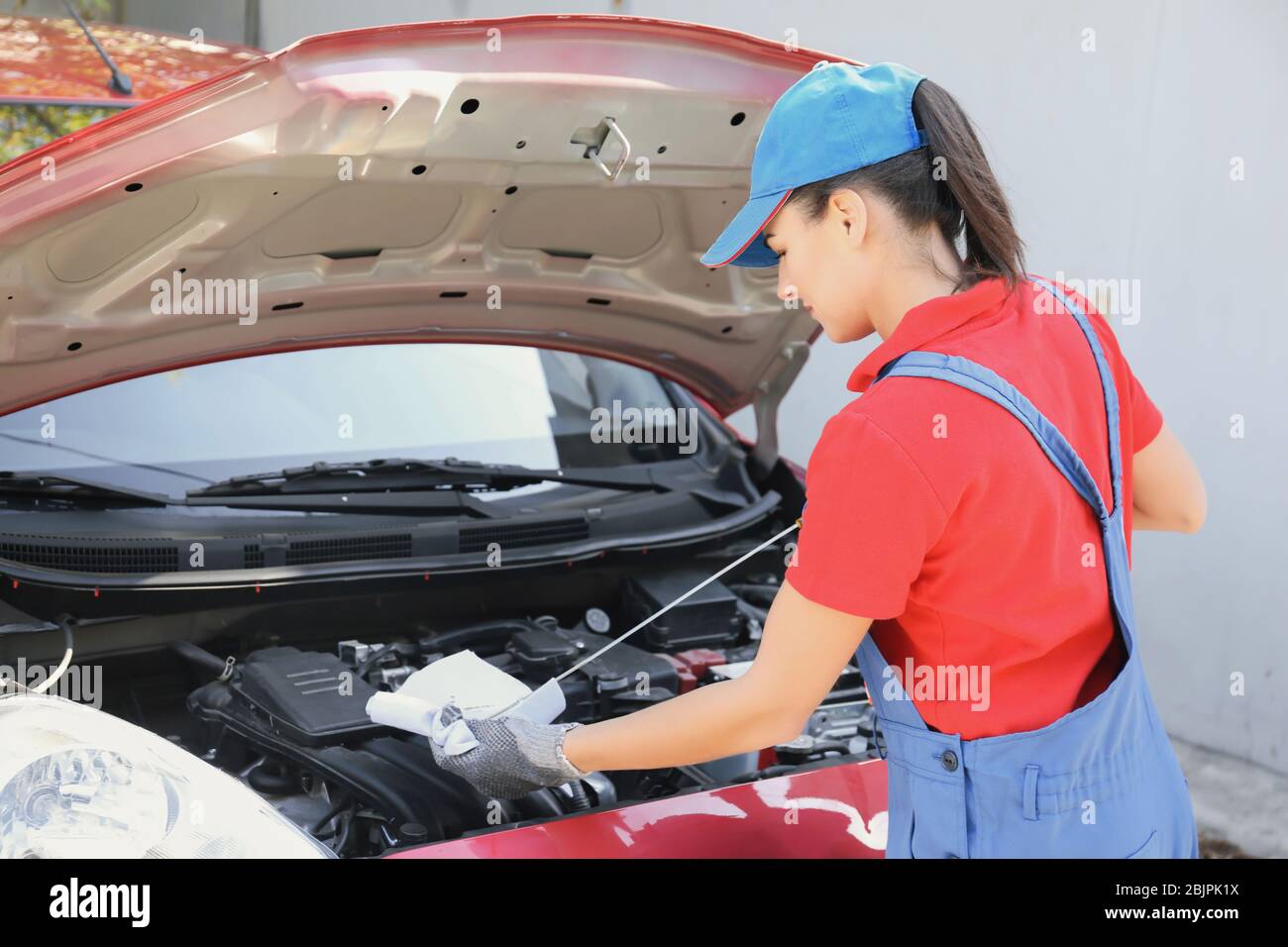 Young mechanic checking engine oil level outdoors Stock Photo - Alamy