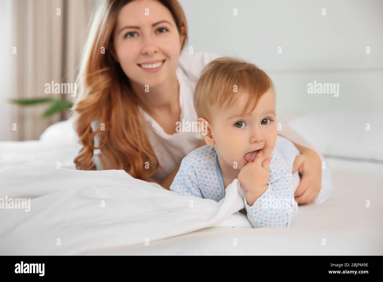 Young mother with baby on bed at home Stock Photo - Alamy