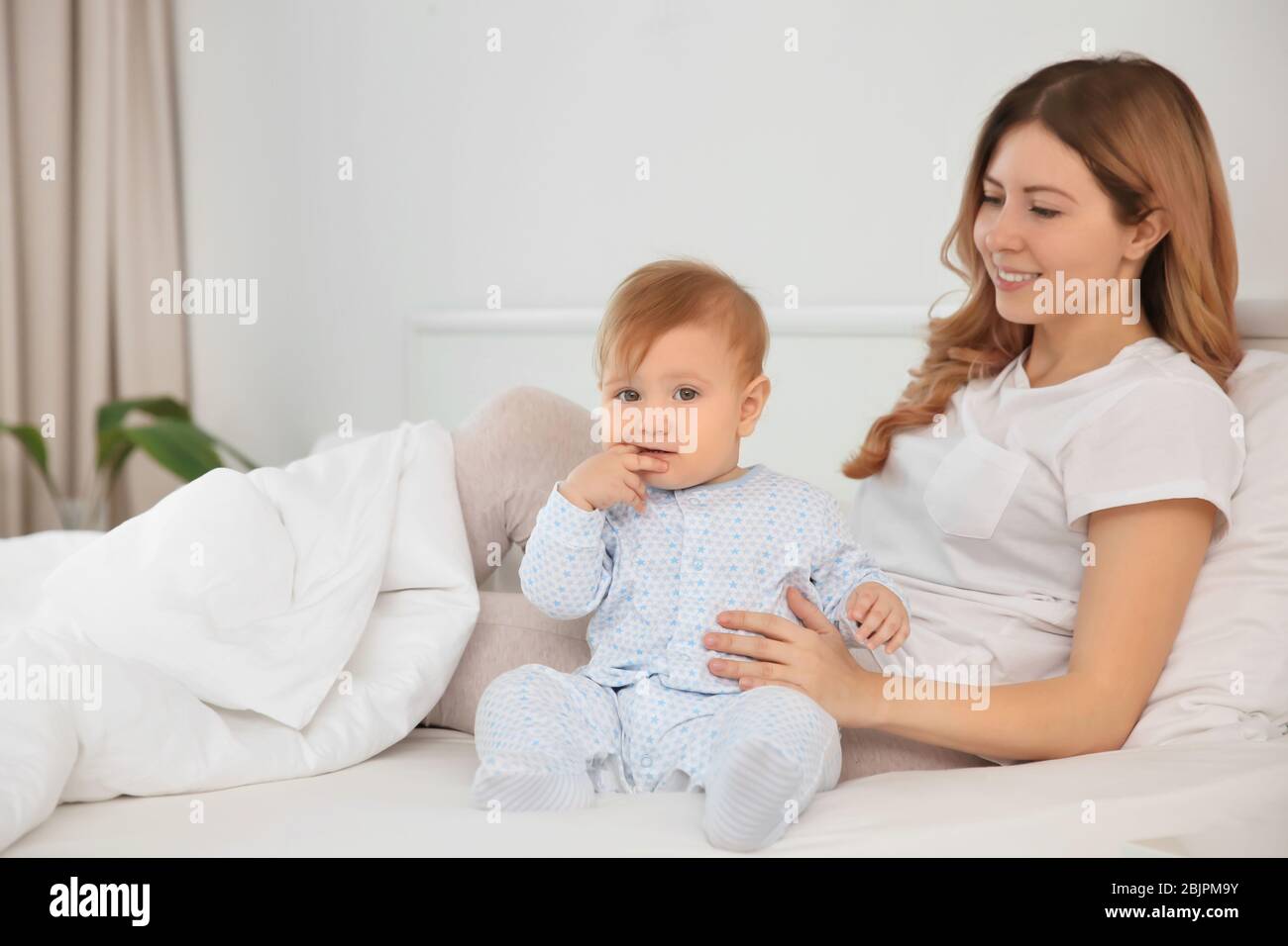 Young mother with baby on bed at home Stock Photo - Alamy