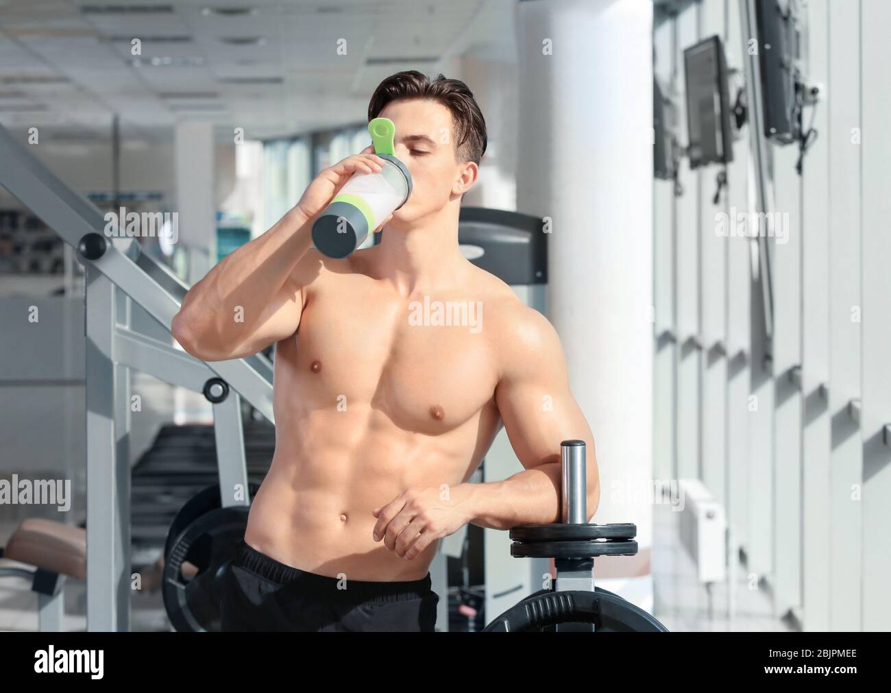 Sporty young man drinking protein shake in gym Stock Photo - Alamy