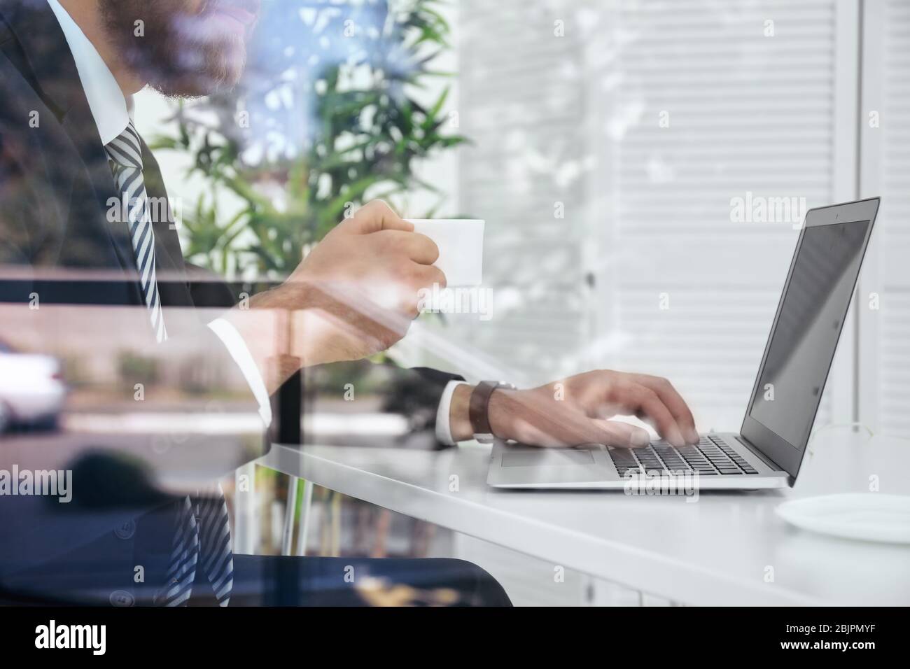 Young businessman using his laptop while working in office, view ...