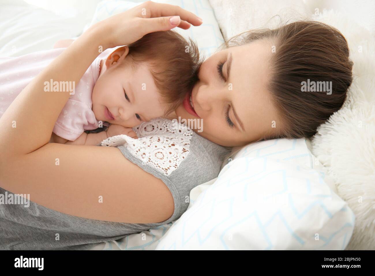 Young mother holding cute little baby on bed at home Stock Photo - Alamy