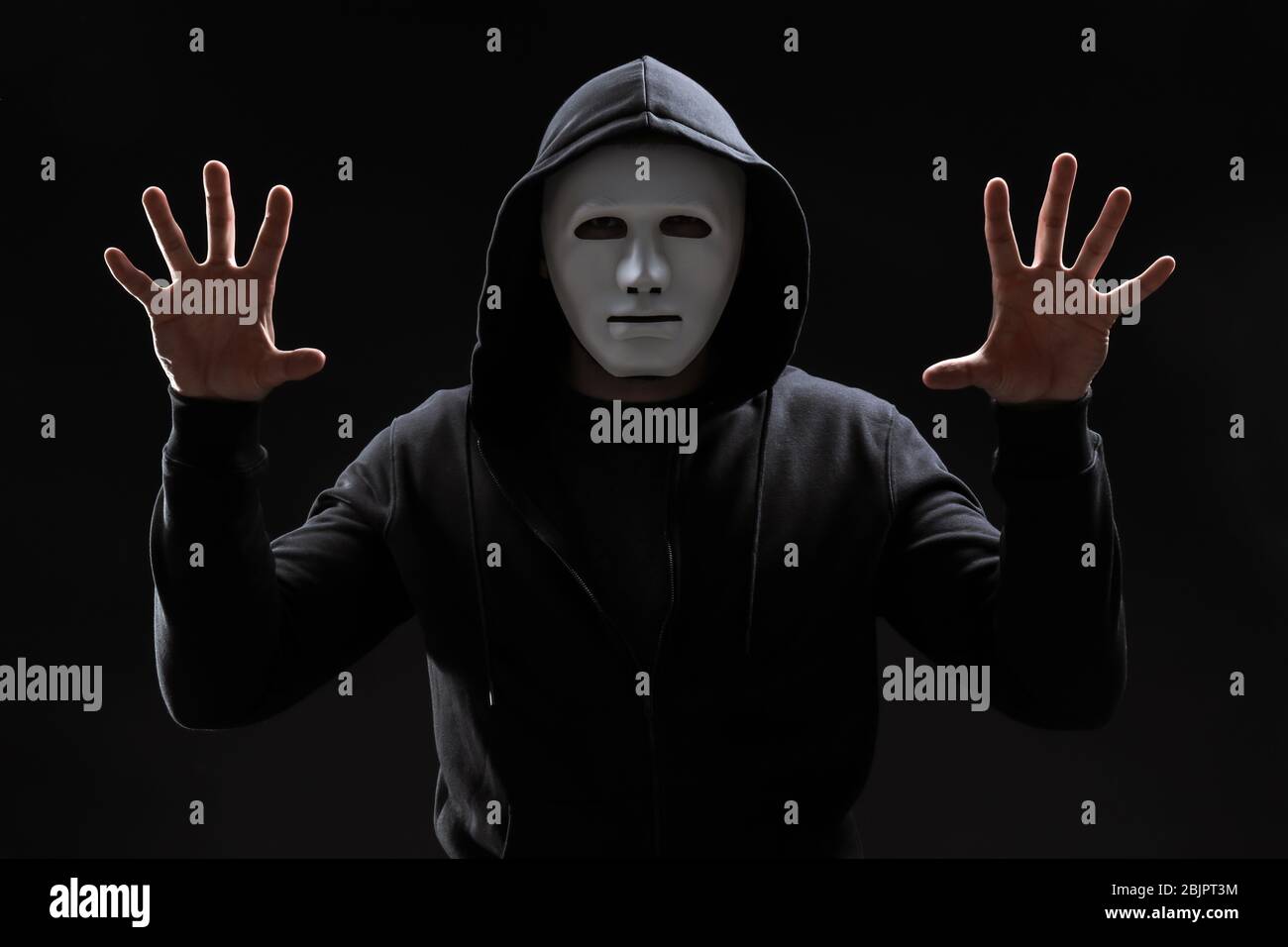 Hacker in mask working with virtual screen on dark background Stock ...