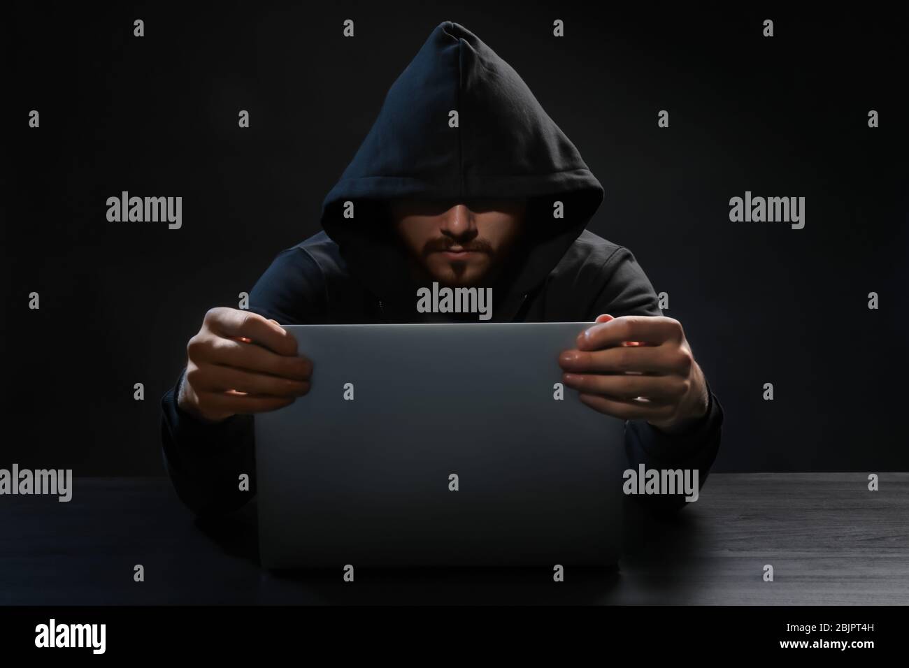 Hacker using laptop on dark background Stock Photo - Alamy