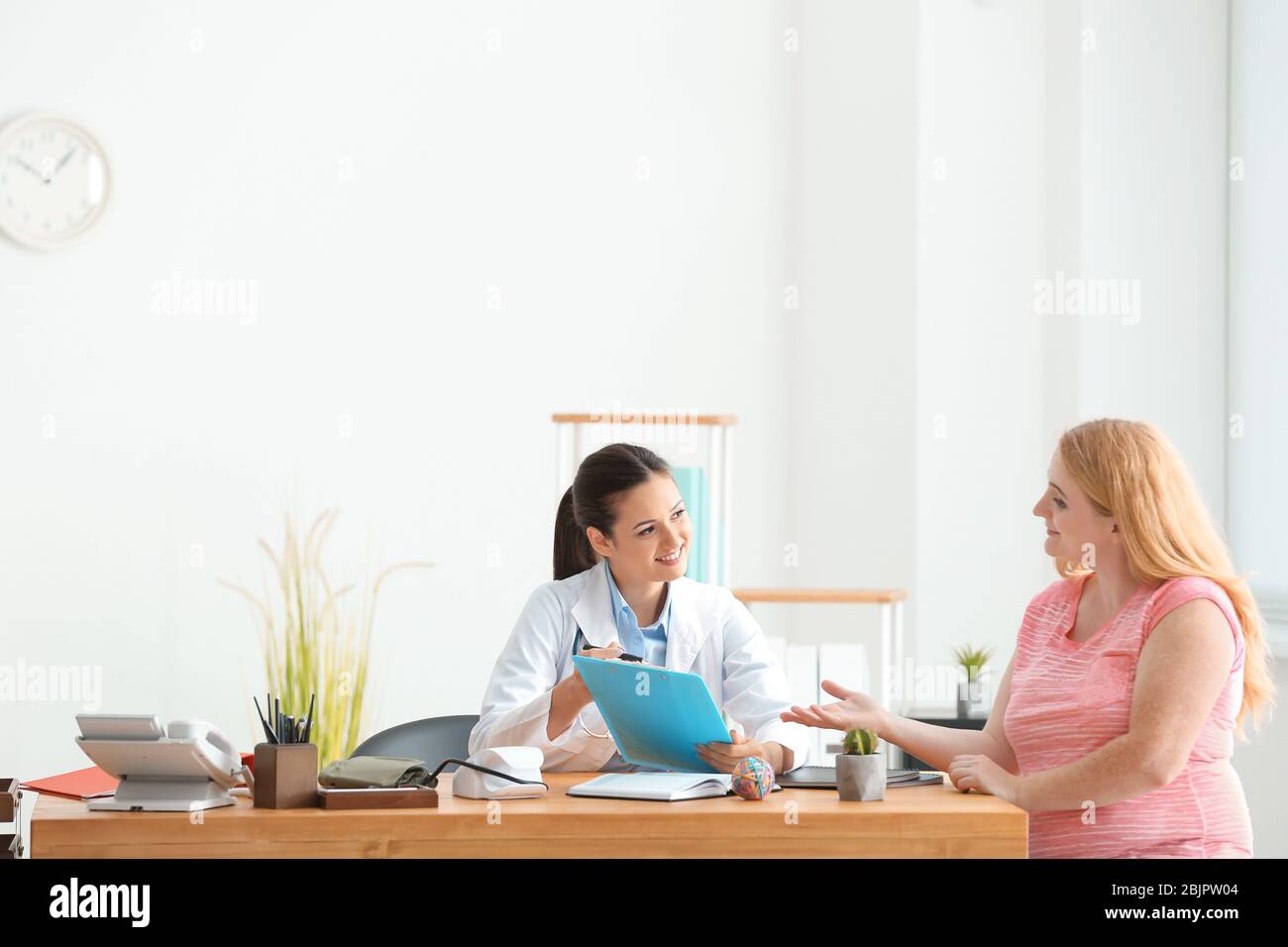 Young female doctor consulting overweight woman in clinic Stock Photo ...