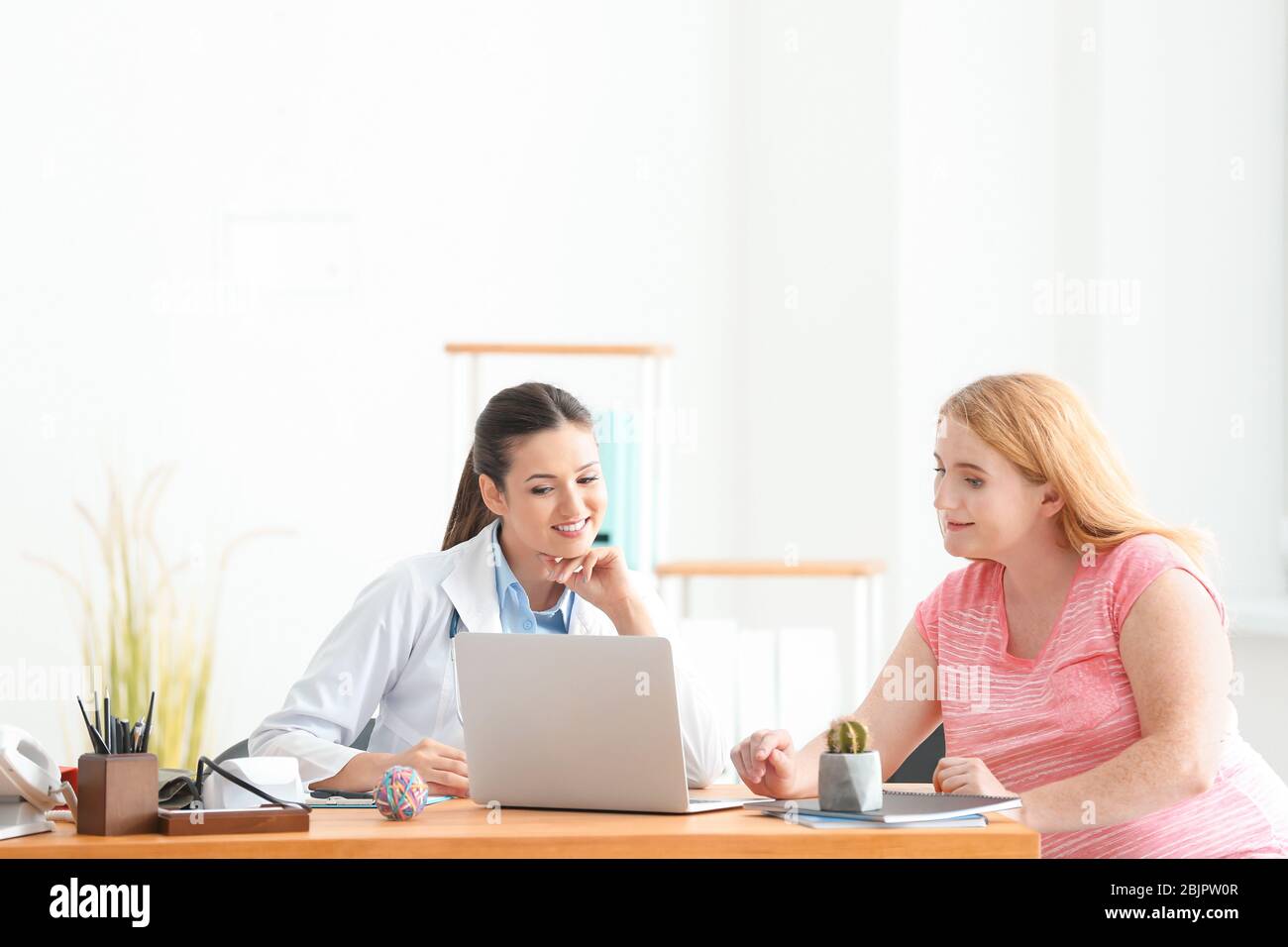 Young female doctor consulting overweight woman in clinic Stock Photo ...
